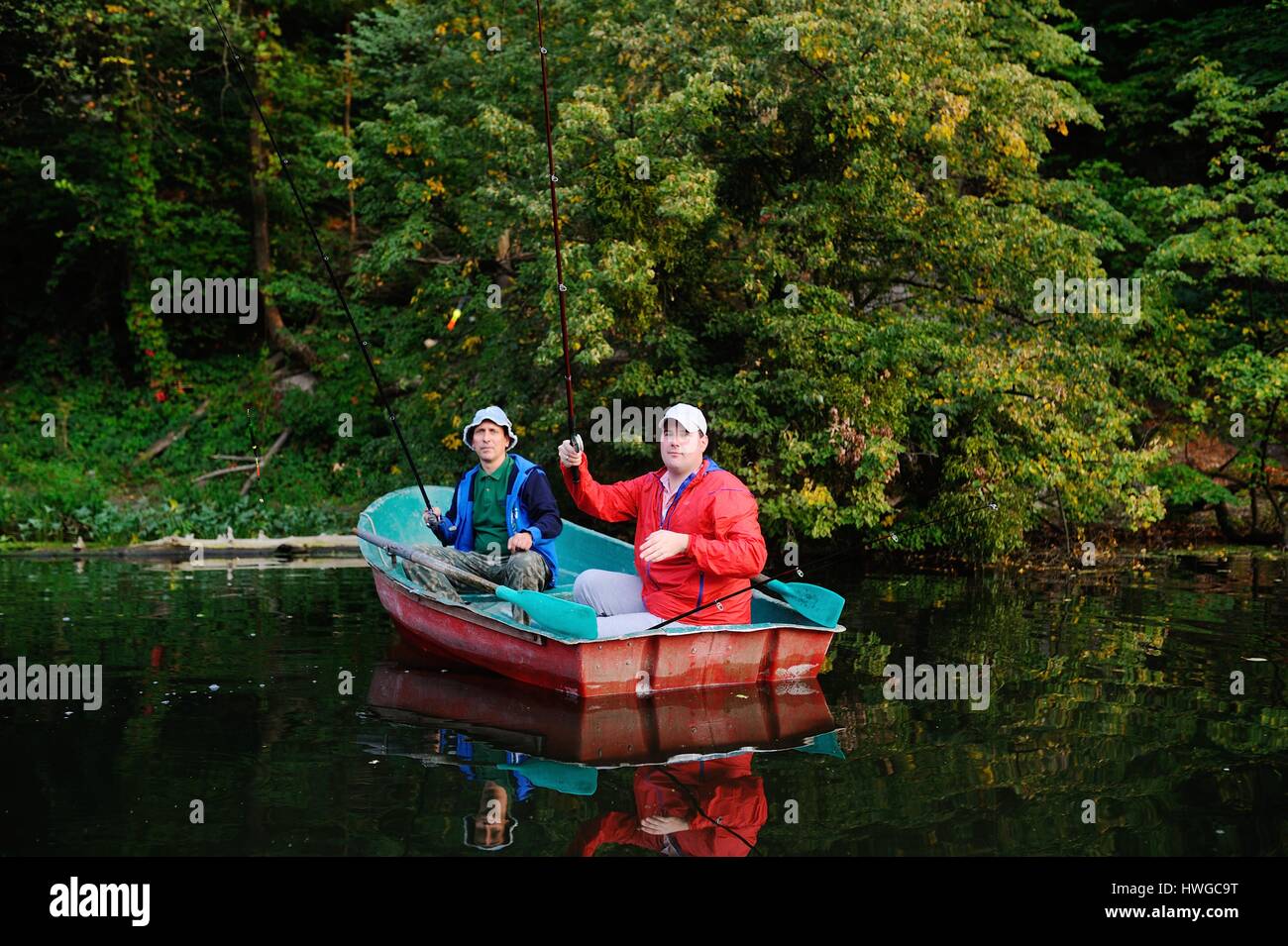 Two fishermen in a boat with fishing rods catching fish Stock Photo - Alamy
