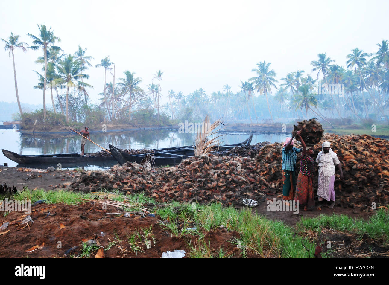 A coir worker approaches land with ratted husk on his boat, while other ...