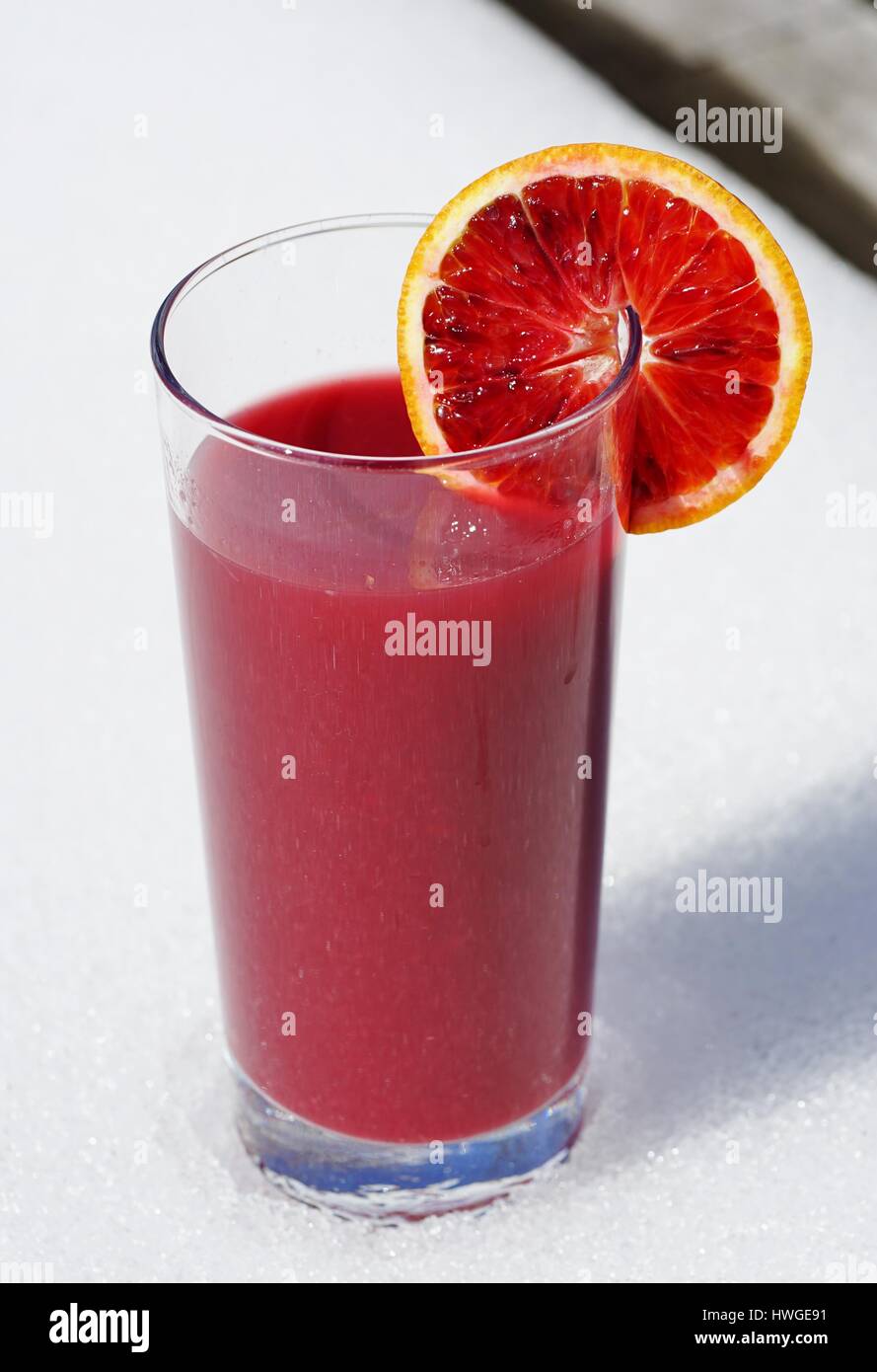 A glass of fresh ruby red blood orange juice with a blood orange slice ...