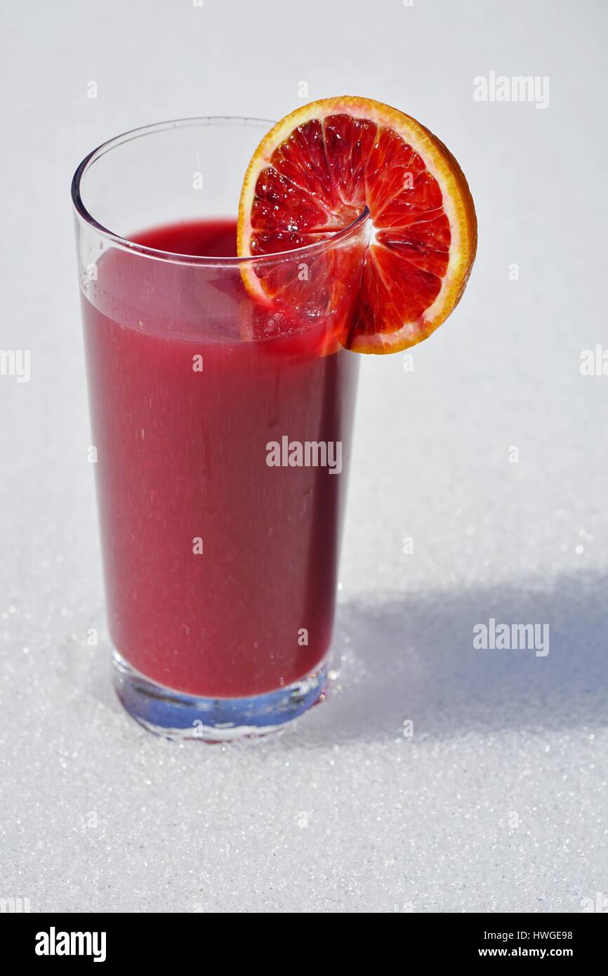 A glass of fresh ruby red blood orange juice with a blood orange slice ...