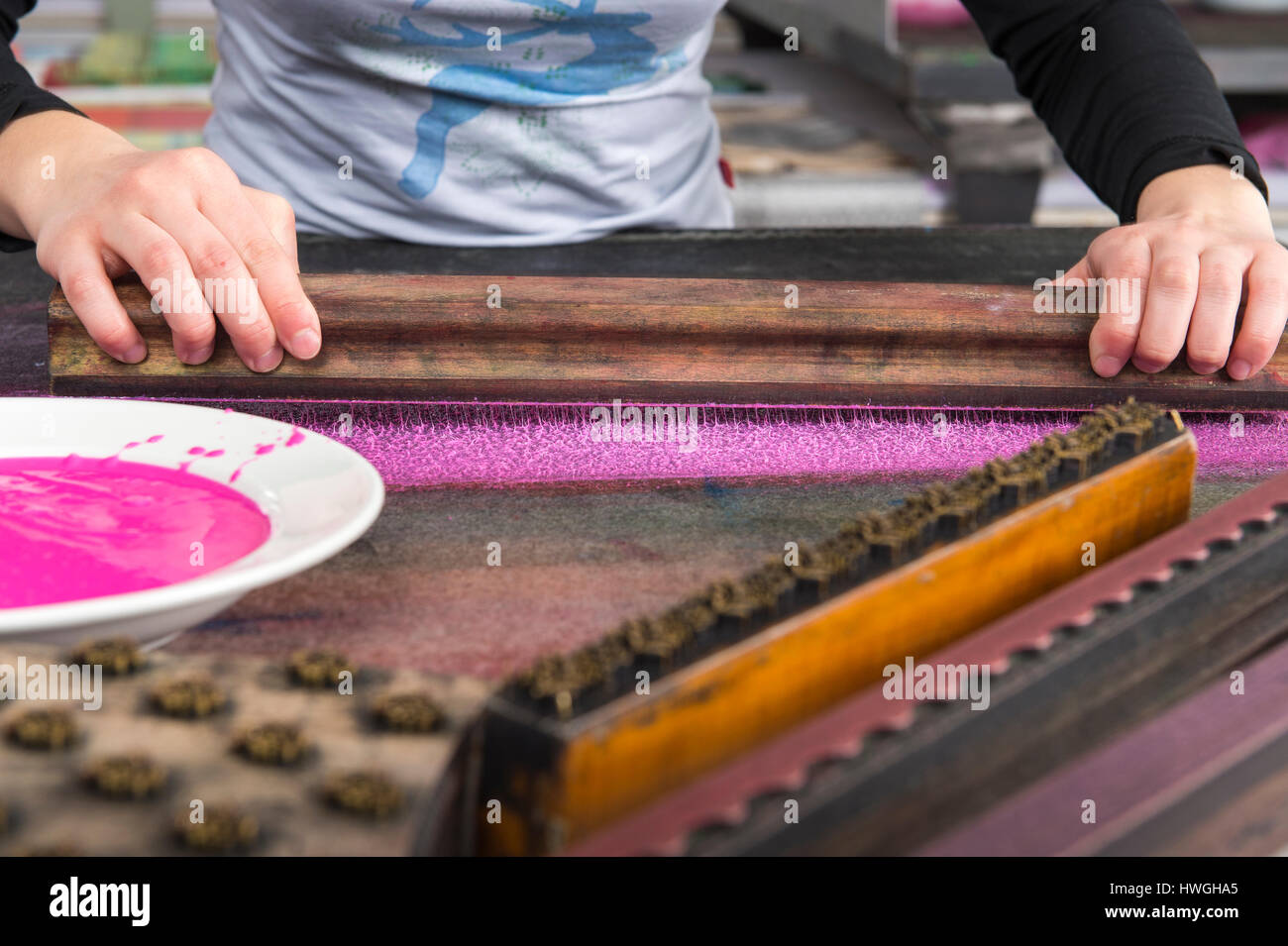 Block printing, hands pressing woodblock on color on felt mat ...