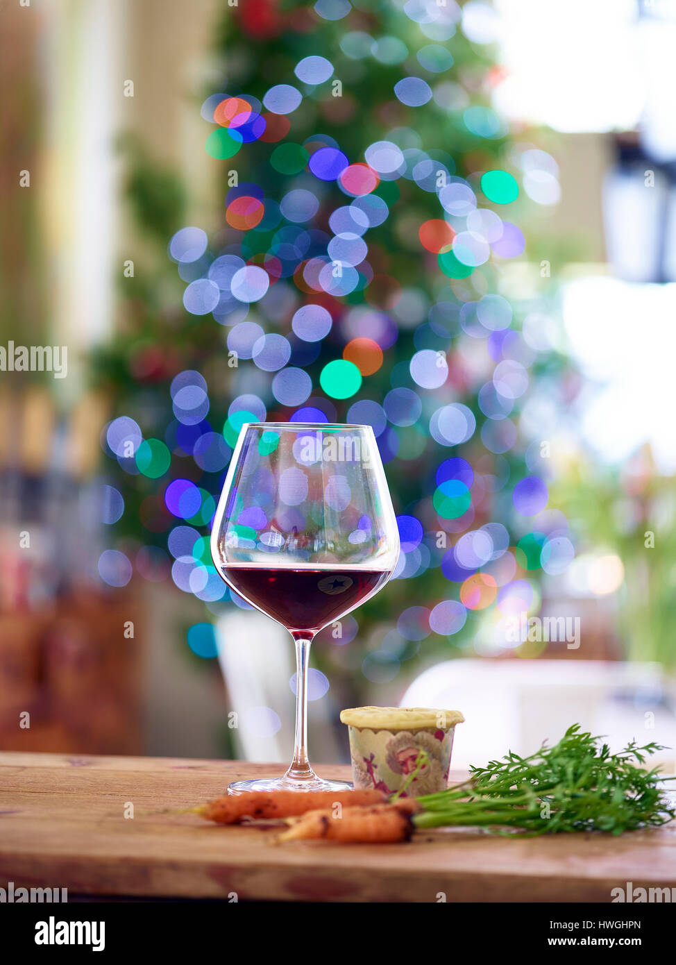 red wine glass in front of Christmas trees with decoration lights treat ...