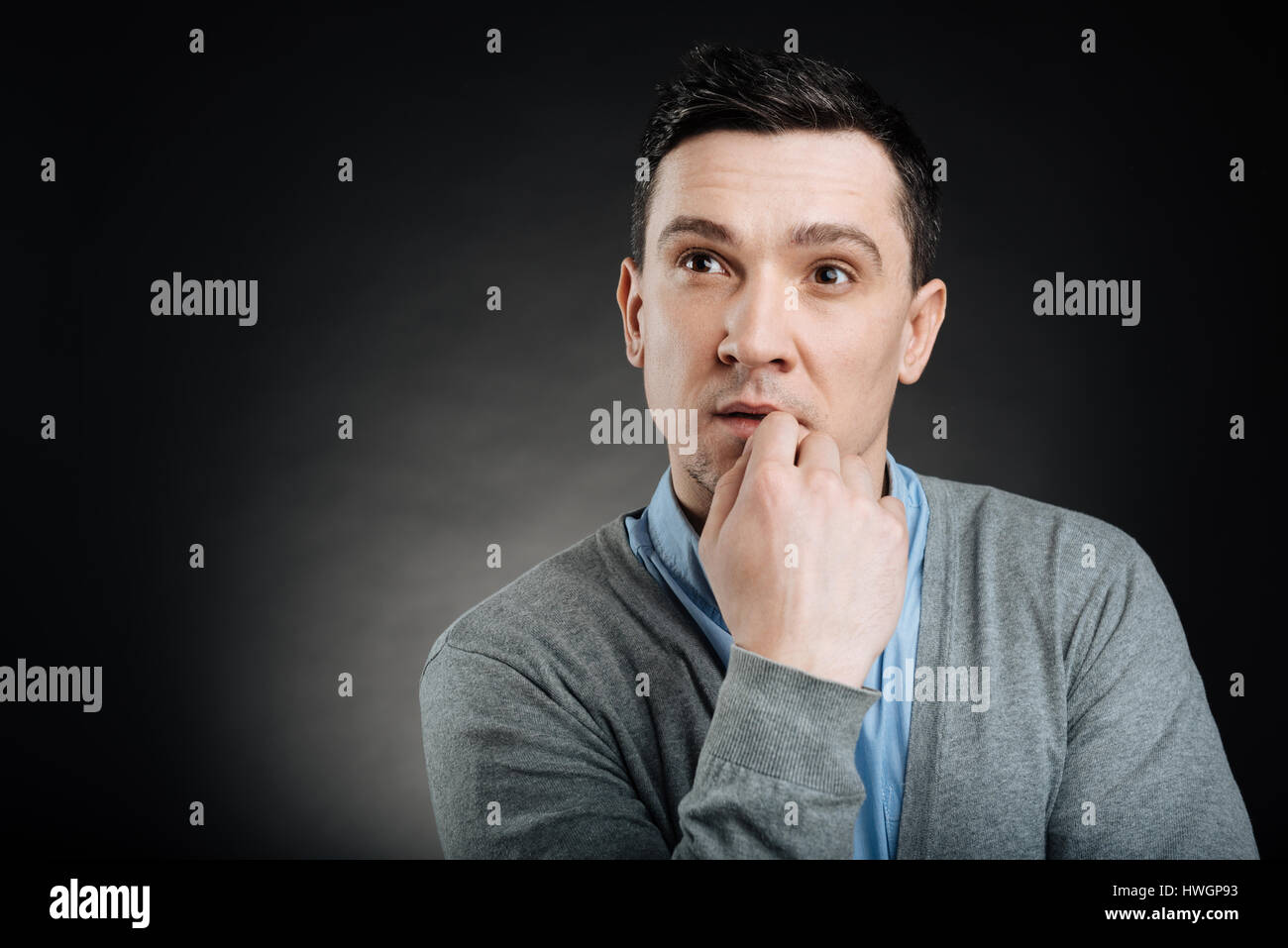 Attractive young man holding hand near mouth Stock Photo - Alamy