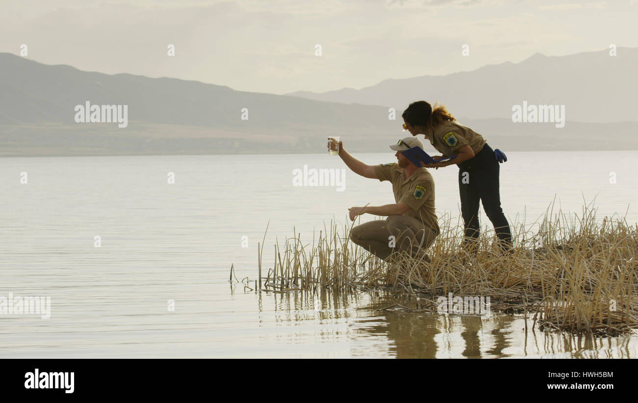 Profile of scientists working together and examining water sample in ...