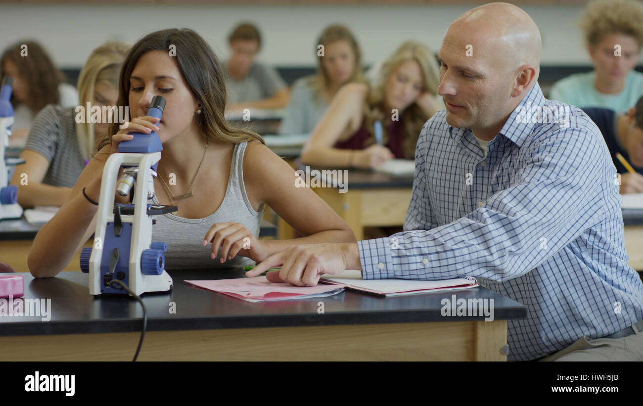 Teacher instructing student using microscope for scientific experiment ...
