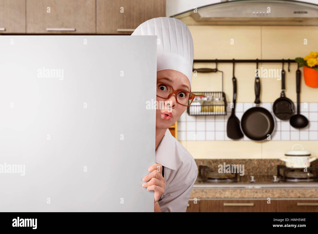 Young asian woman chef standing from behind white board on kitchen room ...