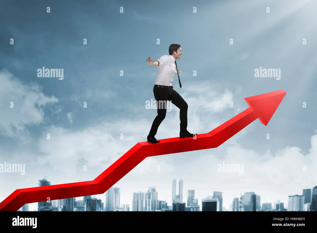 Asian business man balancing increasing arrow chart Stock Photo - Alamy