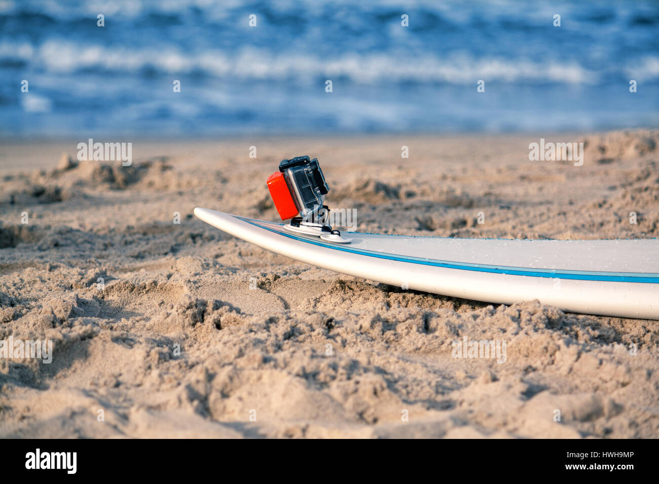 Surfboard with attached action camera lies on the sand on the beach ...