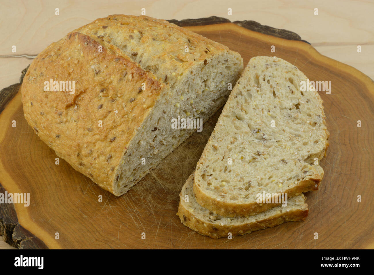 Loaf and slices of nine grain wholegrain bread on wood cutting board ...