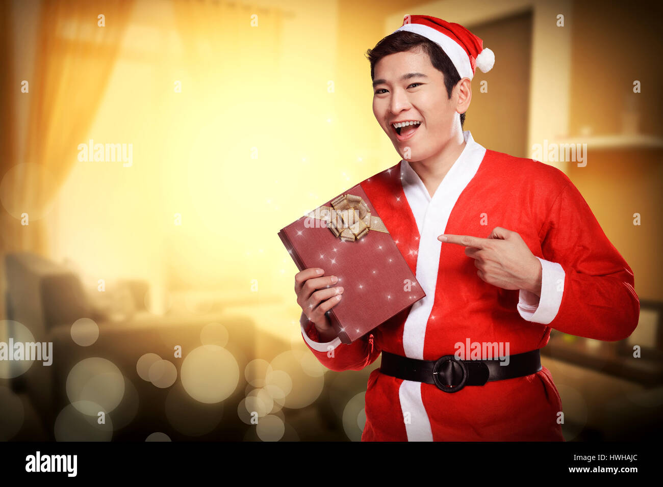 Handsome asian man wearing costume as santa claus, holding gift box ...
