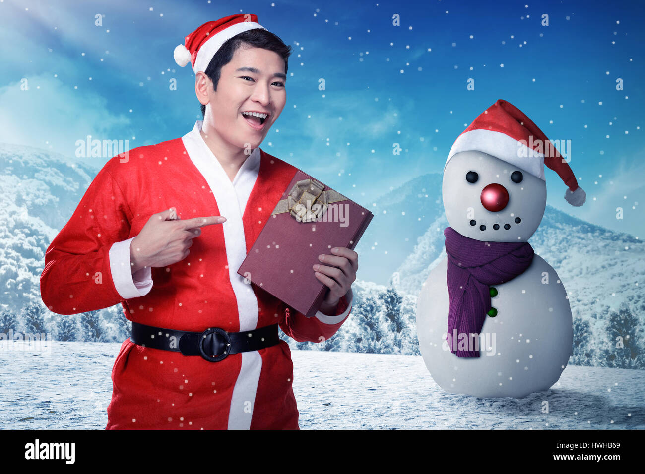 Asian man in santa claus costume holding gift box with winter ...
