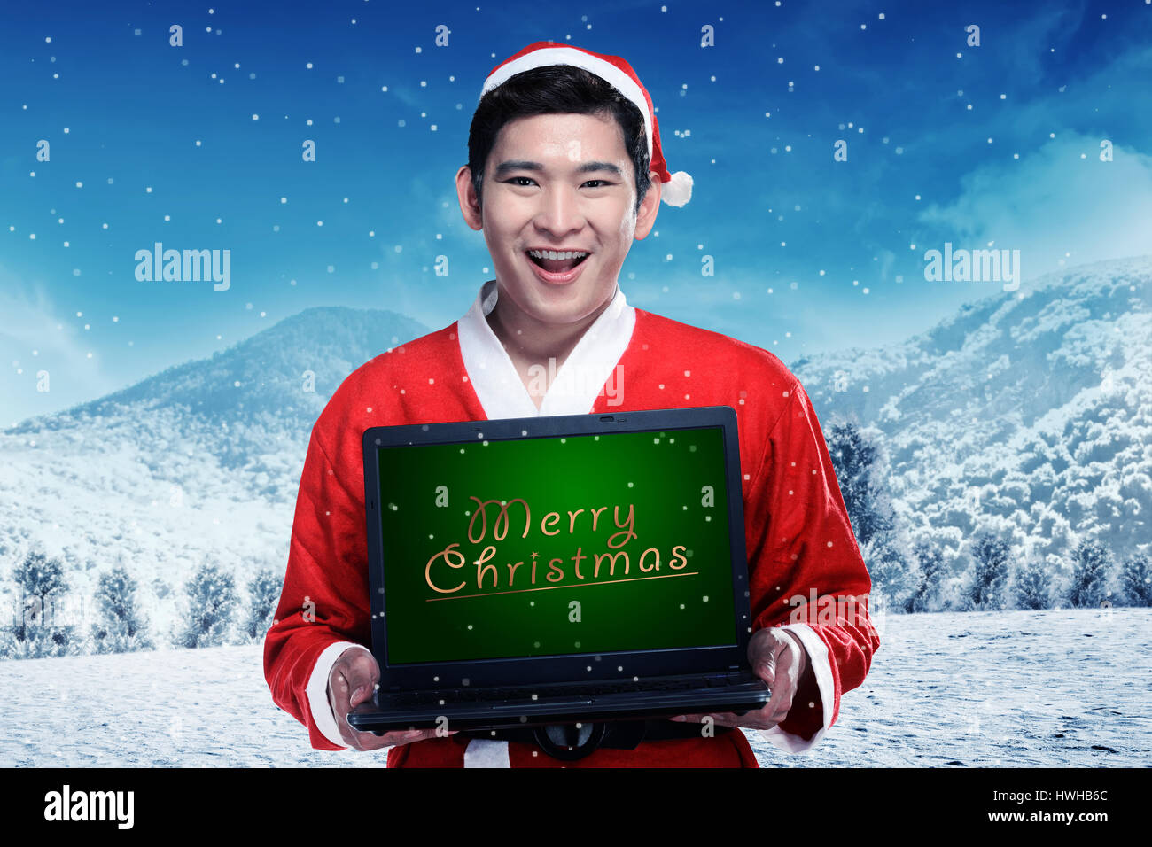 Asian man in santa claus costume holding laptop with merry christmas ...