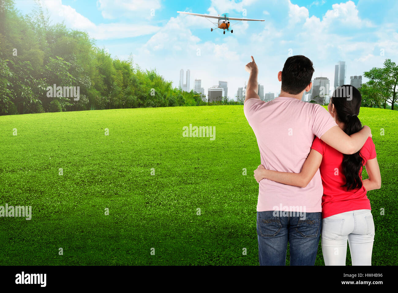 Asian couple pointing propeller plane on the city park Stock Photo - Alamy