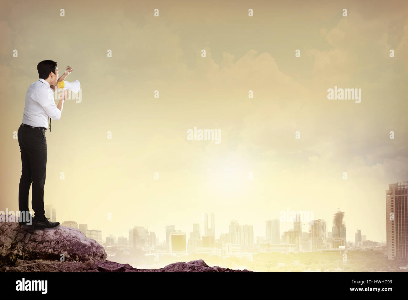 Asian business man standing on the top of mountain, screaming using ...