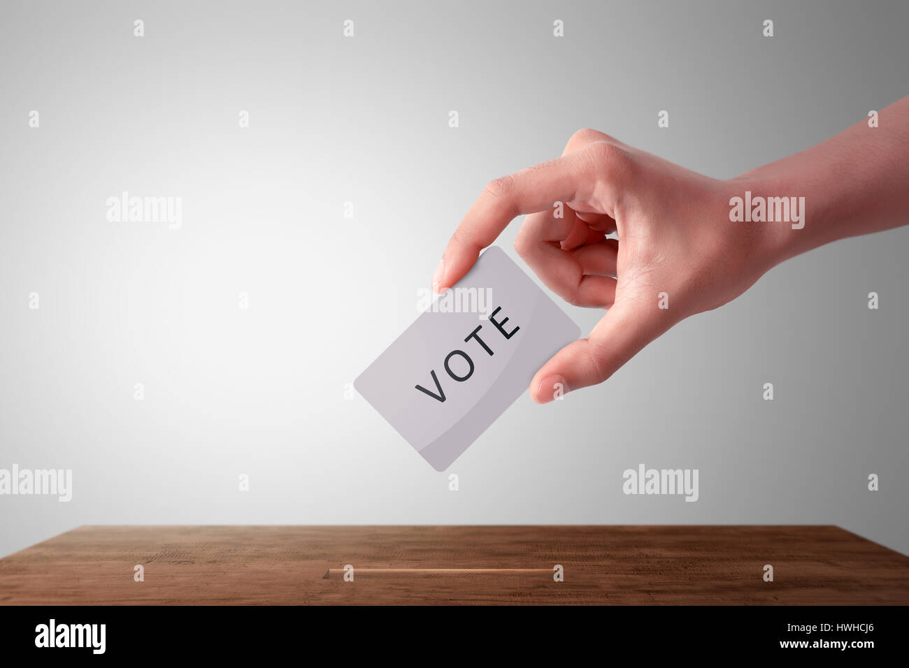 Person hand giving his vote in a ballot box against white background ...