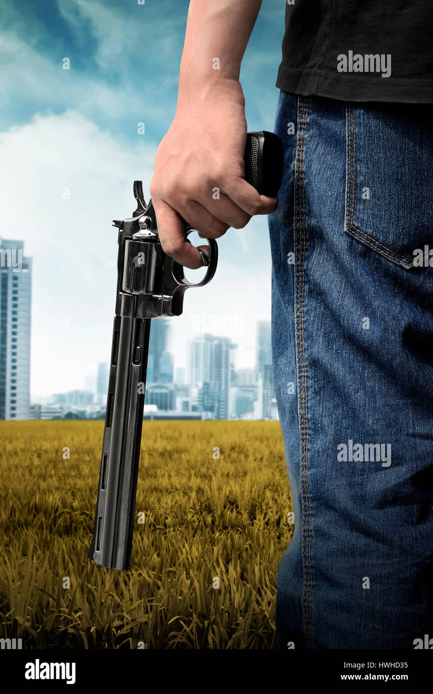 Man hand holding gun on the green field Stock Photo - Alamy