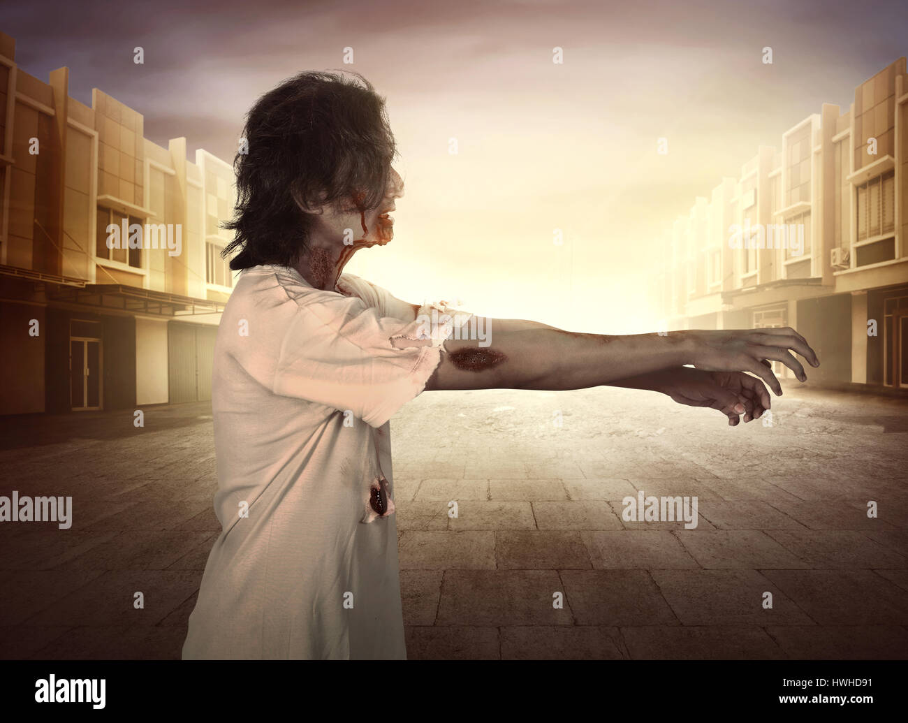 Horrible male zombies walking around the city at sunset Stock Photo - Alamy