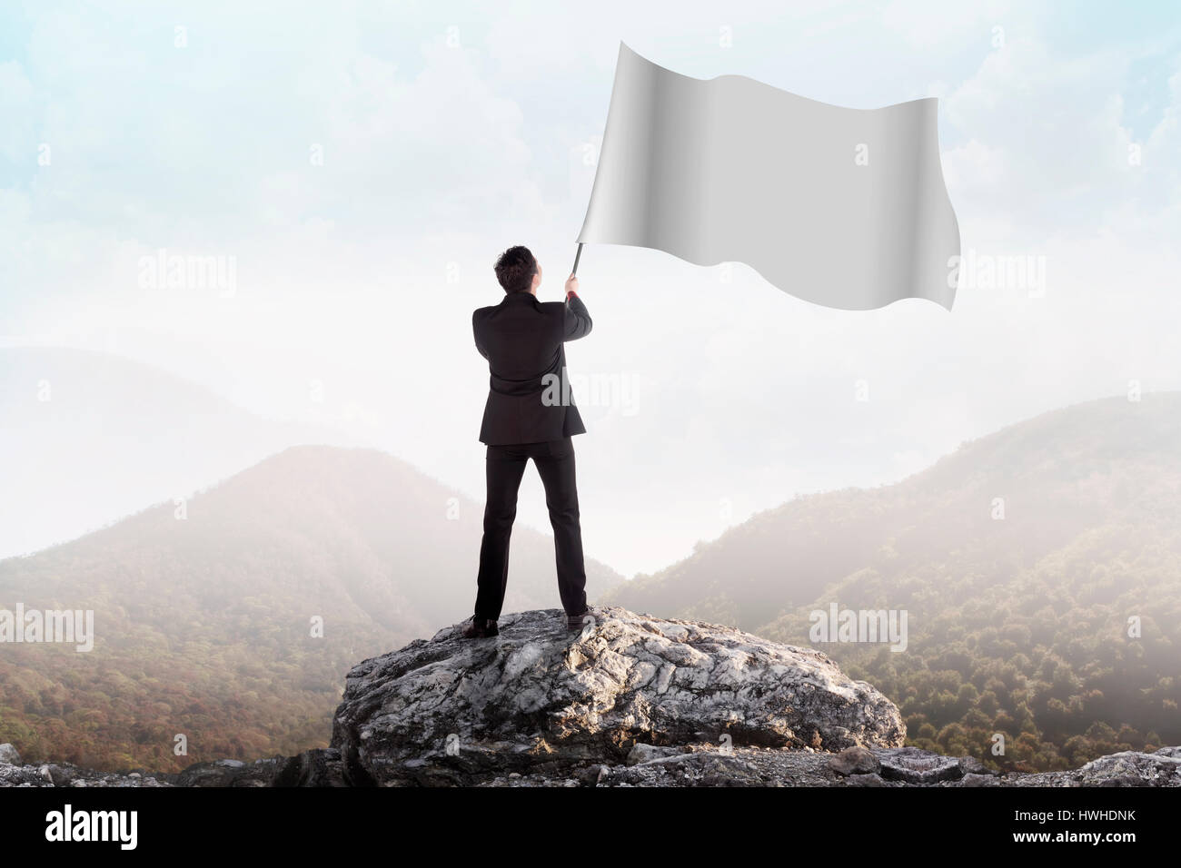 Successful man waving blank flag on the mountain. You can put your ...