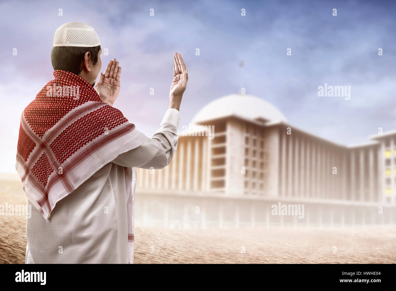 Back view of young muslim man praying looking to mosque Stock Photo - Alamy