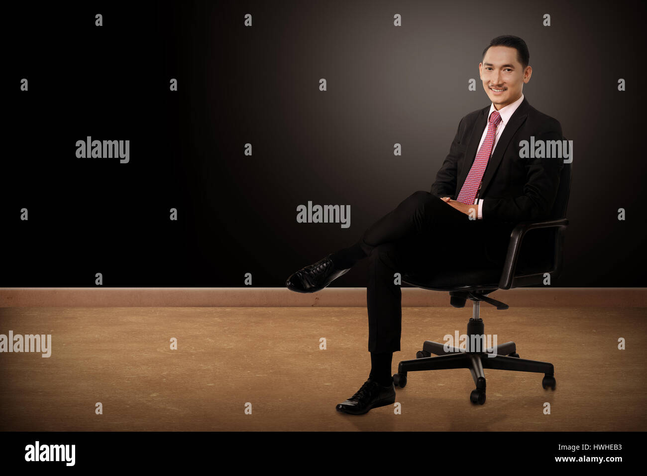 Business man sitting on the chair with black background Stock Photo - Alamy