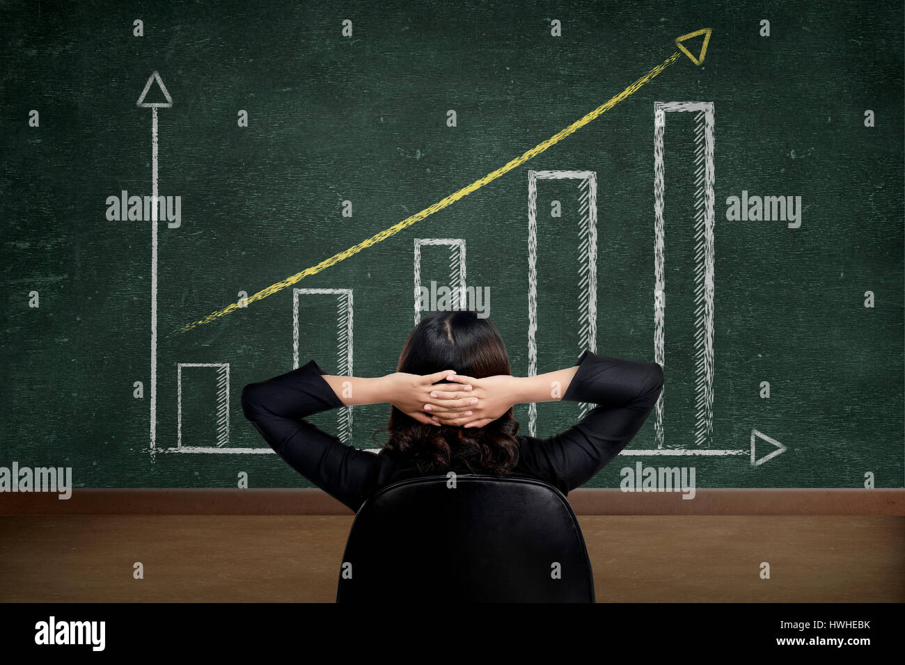Business person smile over increasing graph drawing on chalk board ...