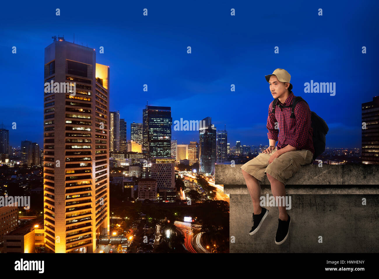 Male tourist sitting on the building rooftop at night time Stock Photo ...