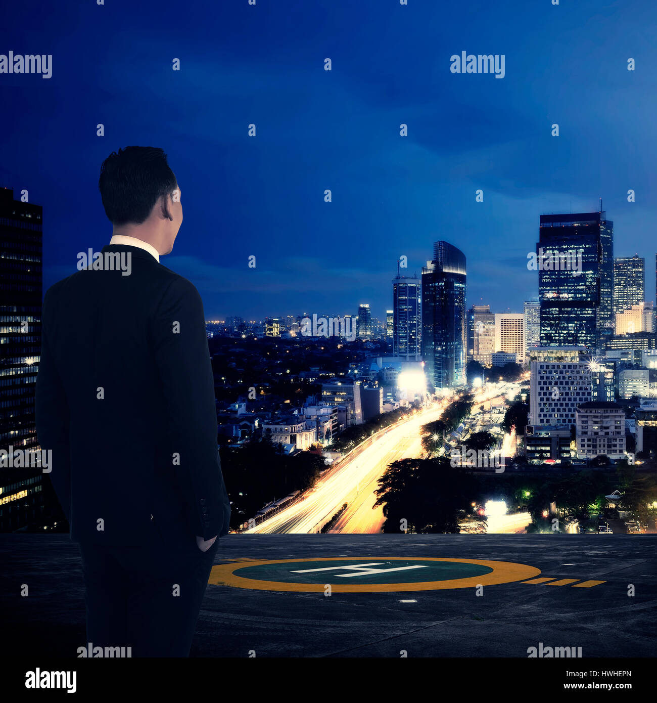 Business man standing on rooftop helipad. Looking at the city. Business ...