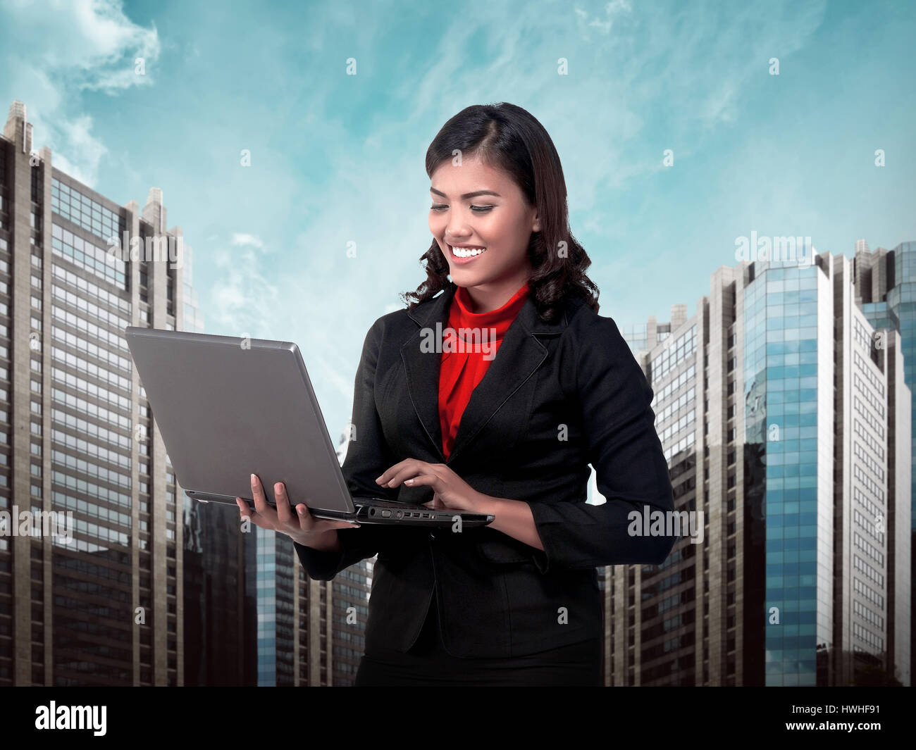 Asian business person typing on laptop over office building background ...