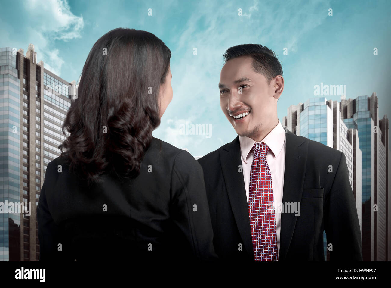 Asian business man and woman shaking hand over office building ...