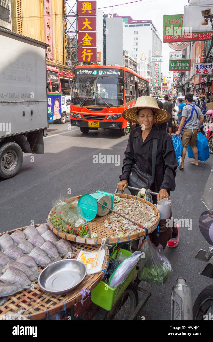 Street vendor pushing her dried fish cart down Yaowarat road in ... Street vendor pushing her dried fish cart down Yaowarat road in ...