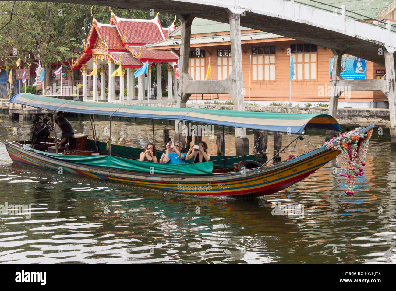 Tourists taking photographs of a temple from a boat on a canal in ...