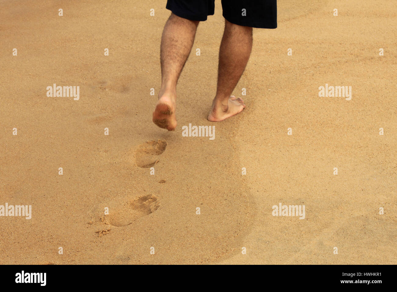 Man walking on the beach leaving footprints on the sand Stock Photo - Alamy