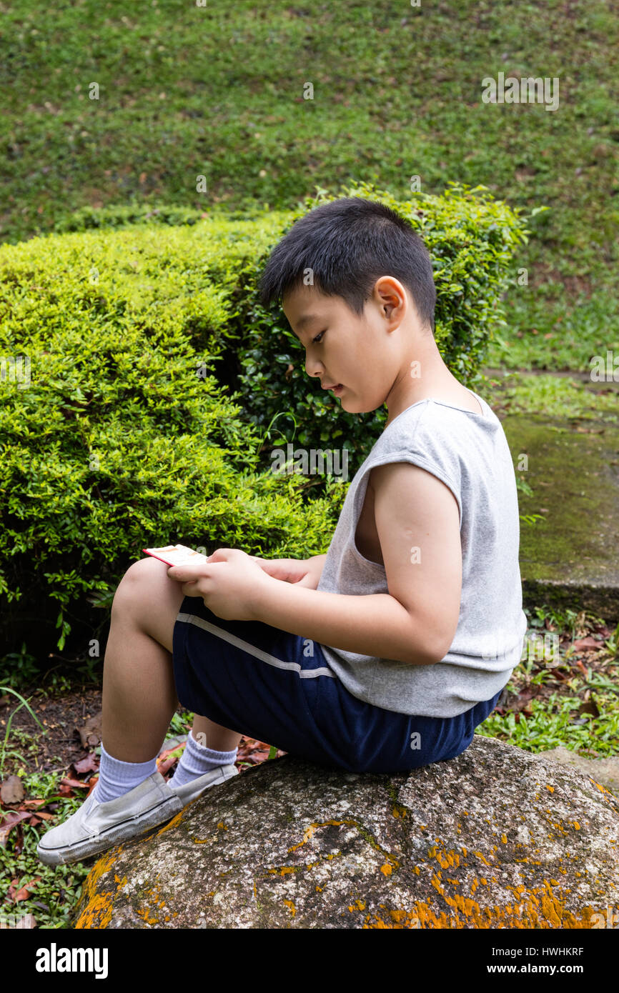 Asian Chinese little boy reading book in the outdoor park Stock Photo ...