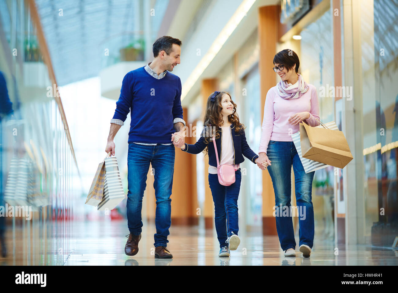 Parents and their daughter walking down modern mall Stock Photo - Alamy