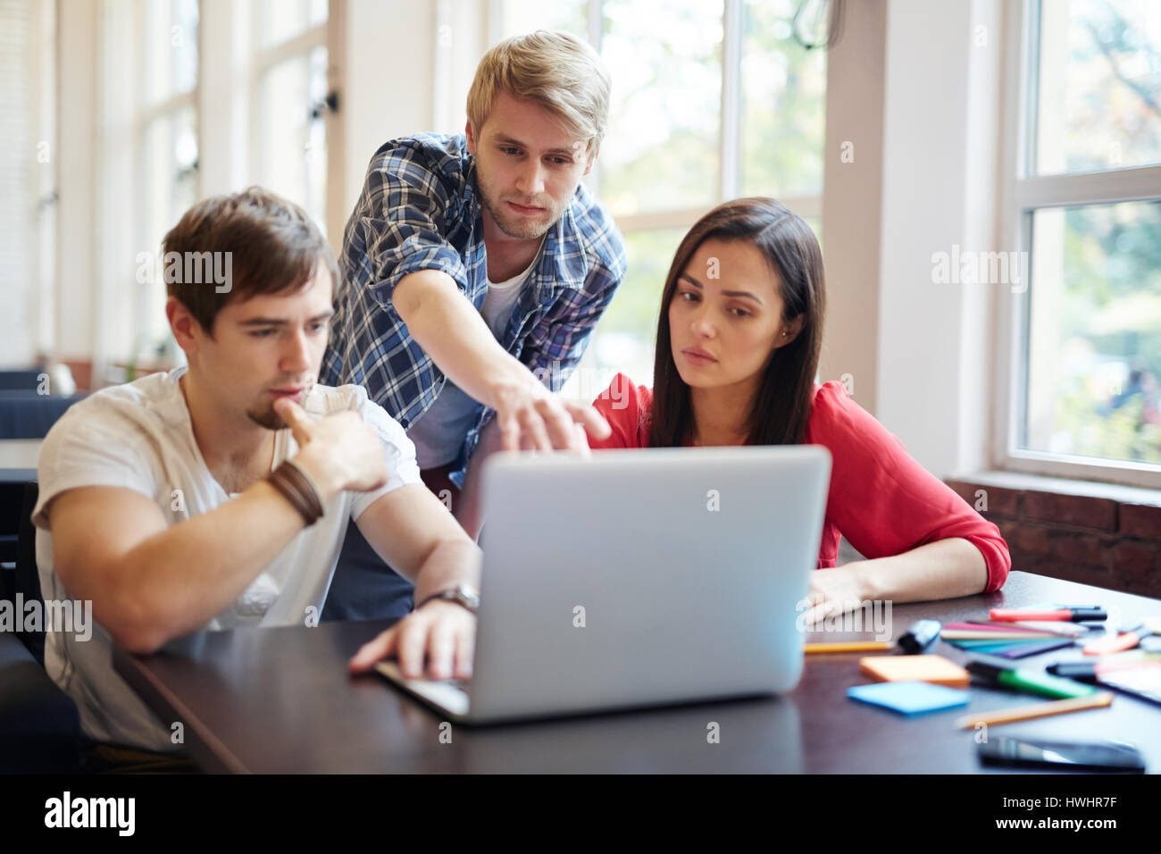 Three business people looking at data on laptop screen Stock Photo - Alamy