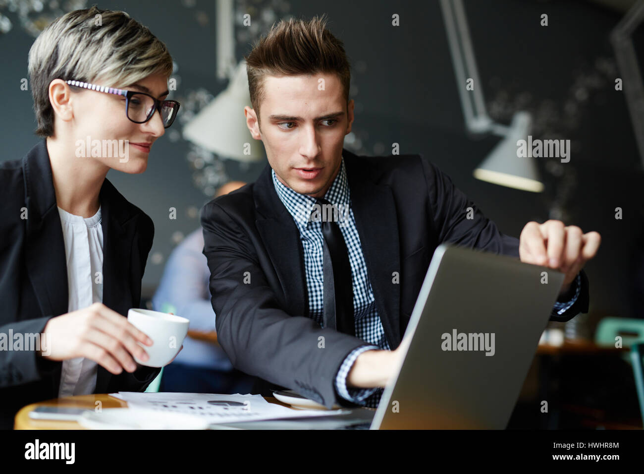 Teamwork in lovely coffeehouse: pretty young businesswoman holding cup ...