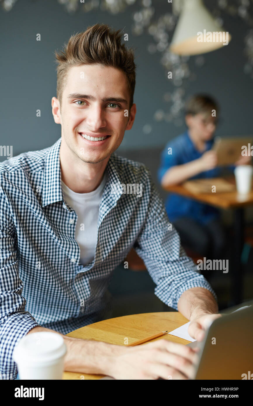 Portrait of handsome university student sitting in cyber cafe and ...