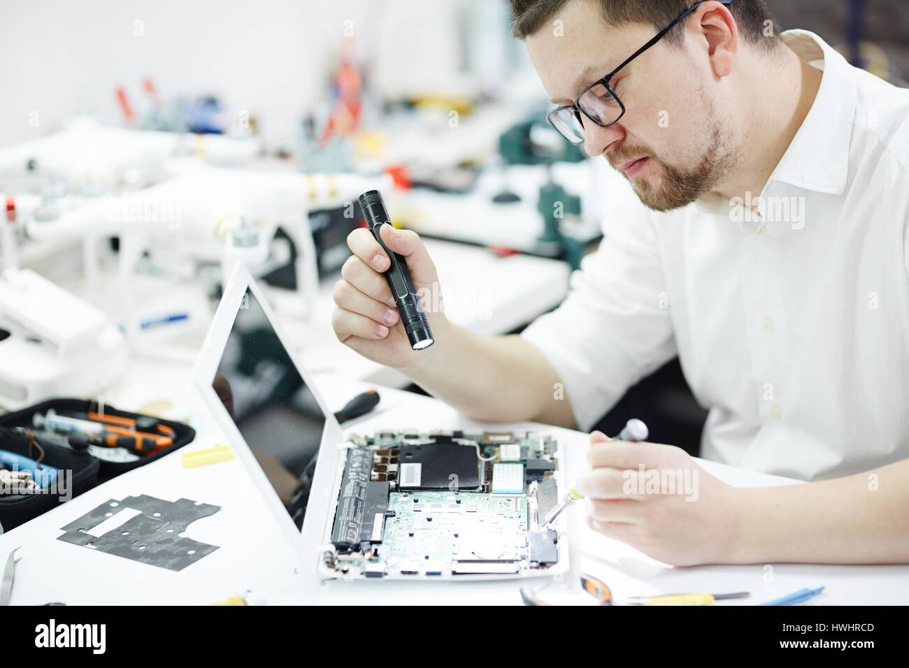 Side view portrait of man opening disassembled computer and using ...