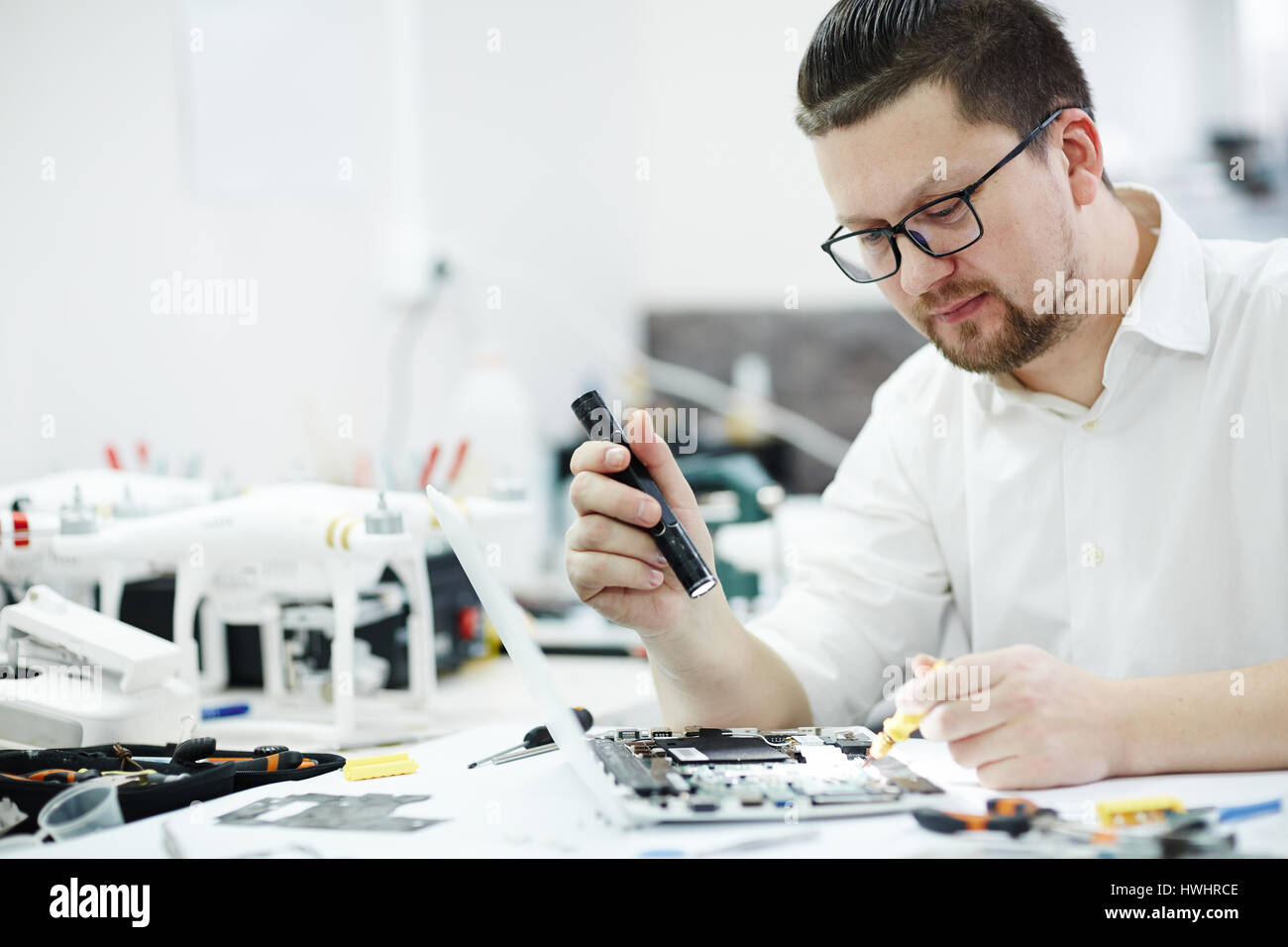 Side view portrait of man inspecting disassembled laptop with ...