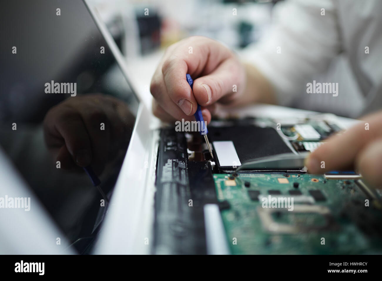 Closeup shot of male hands repairing parts in laptop using screwdriver ...