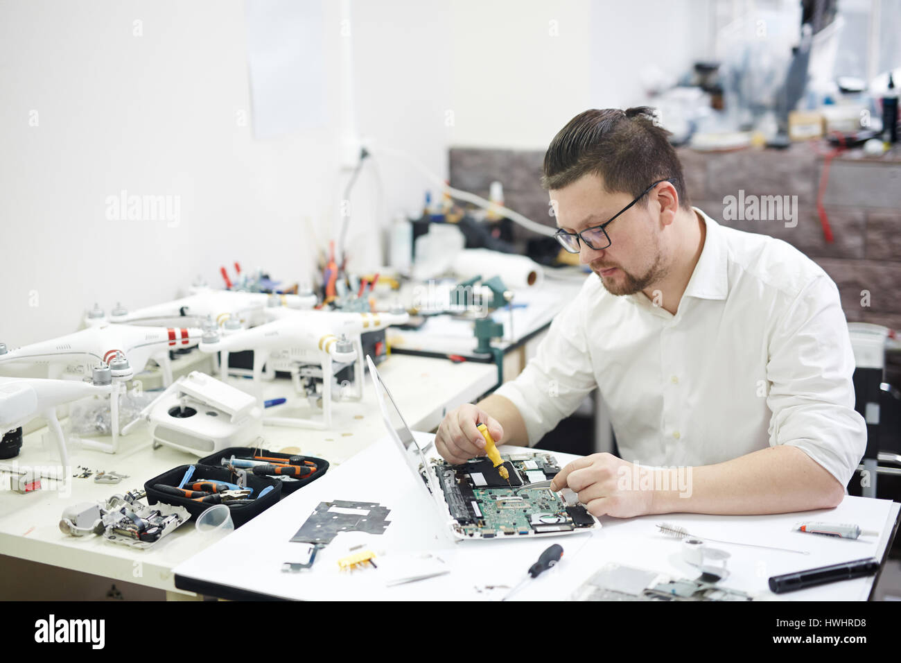 Portrait of modern man wearing glasses busy working with electronics in ...