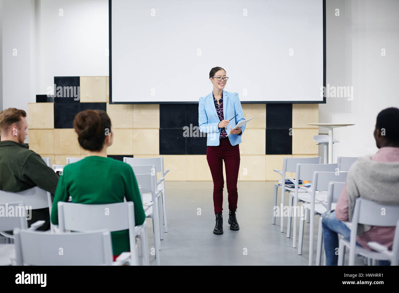 Happy young teacher talking to her students in conference-hall Stock ...