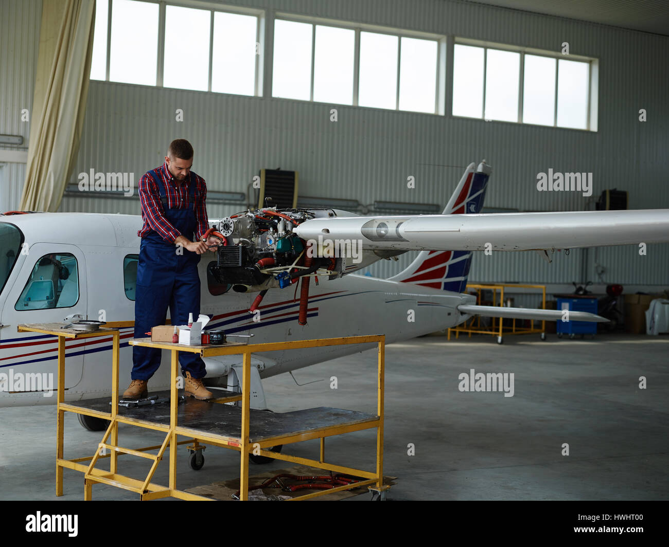 Young man repairing airplane in hangar Stock Photo - Alamy
