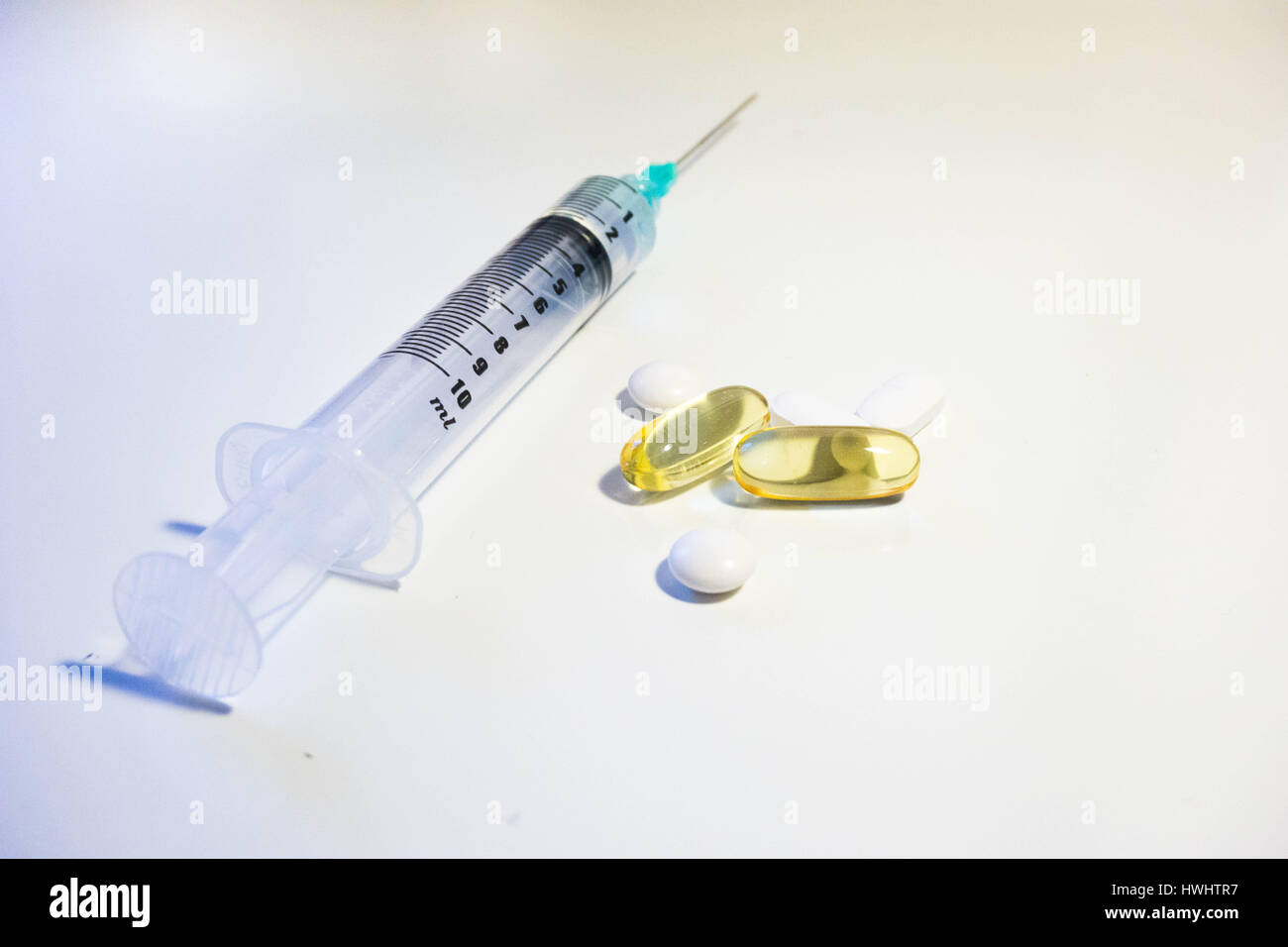 Syringe with green tip containing clear fluid and white and yellow ...