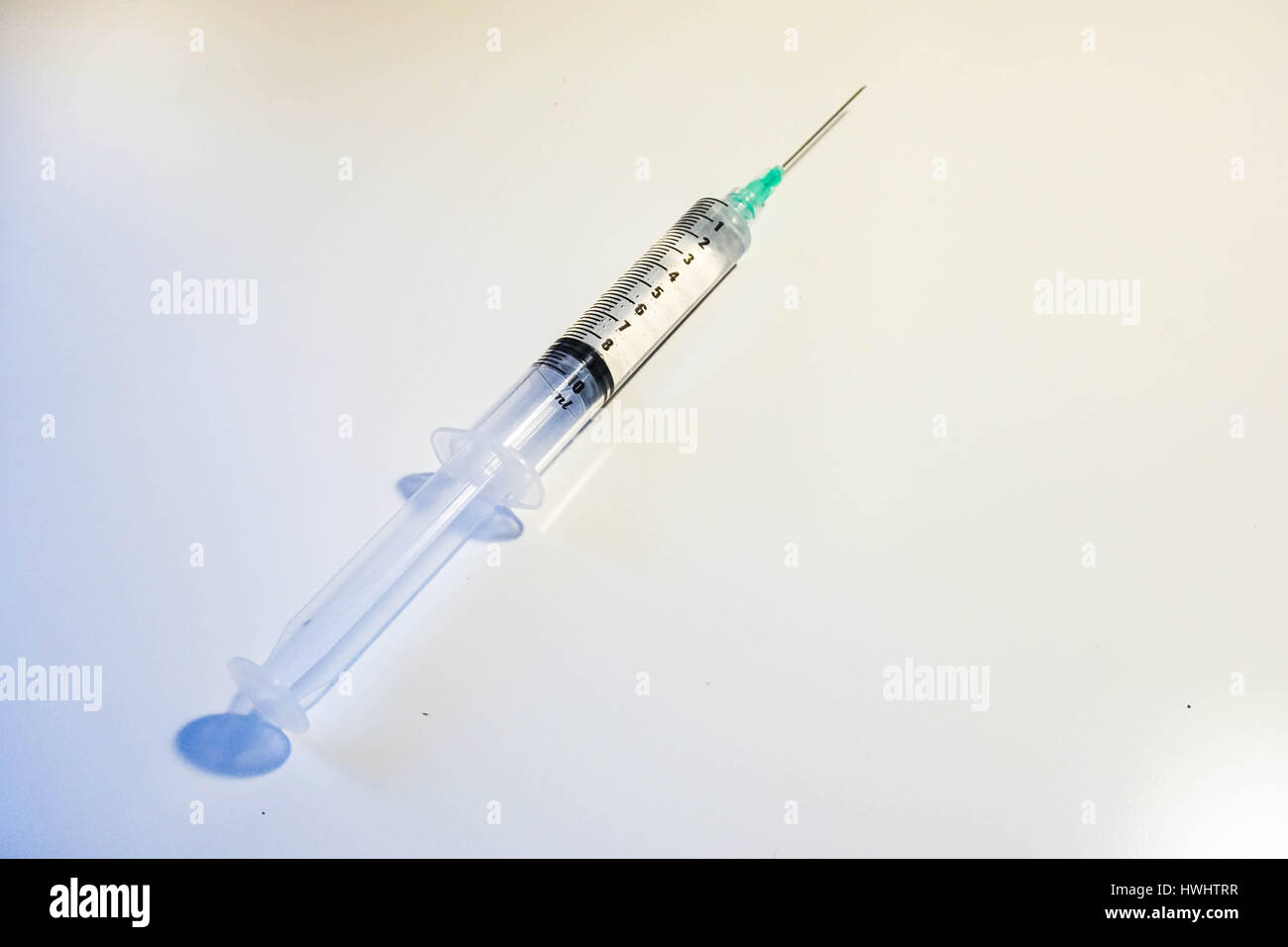 A medical syringe with a green tip is 8ml full of clear fluid against a ...