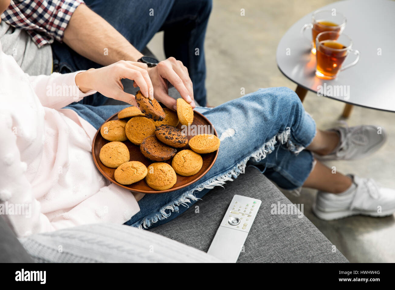 Couple eating biscuits and drinking tea while watching tv Stock Photo ...