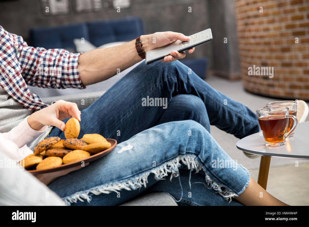 Couple eating biscuits and drinking tea while watching tv Stock Photo ...