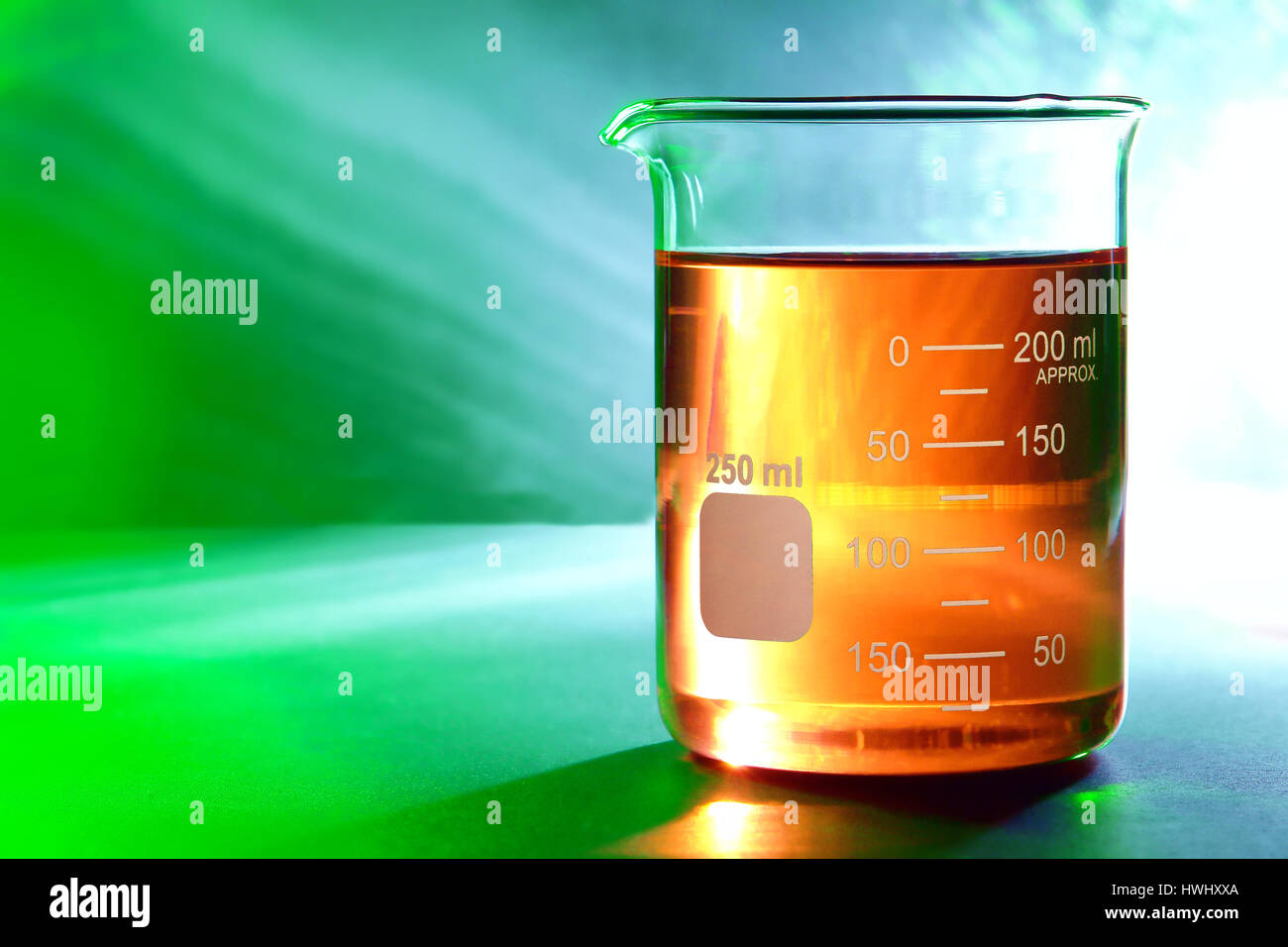 Graduated scientific glass beaker with amber orange chemical liquid ...