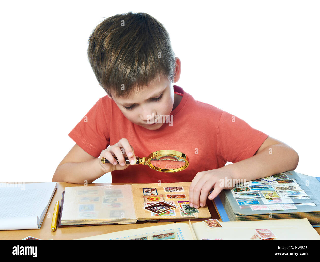 Boy with magnifying glass looks his stamp collection isolated white ...