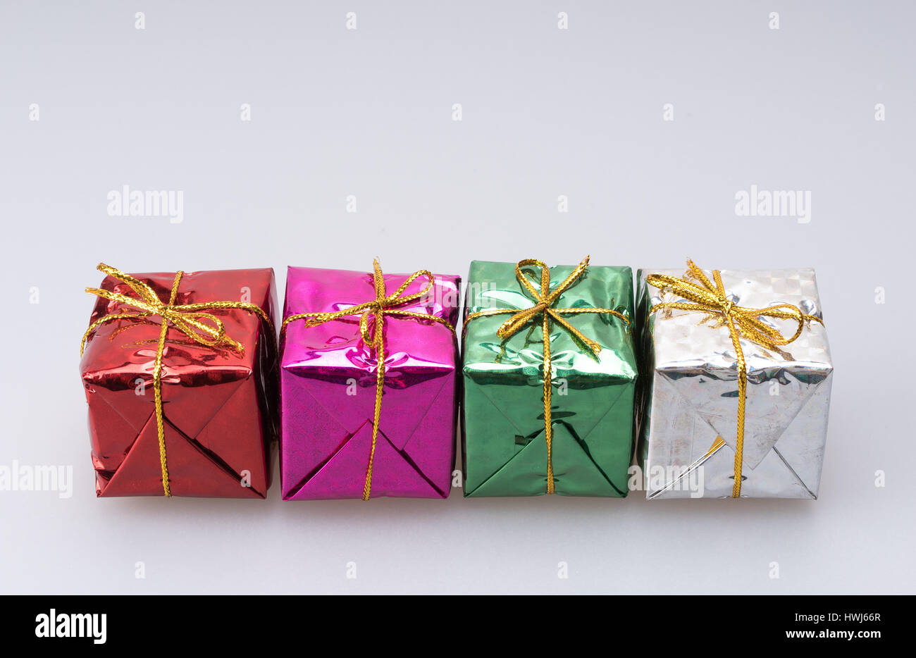 A line of mini presents wrapped in shiny paper in an assortment of ...